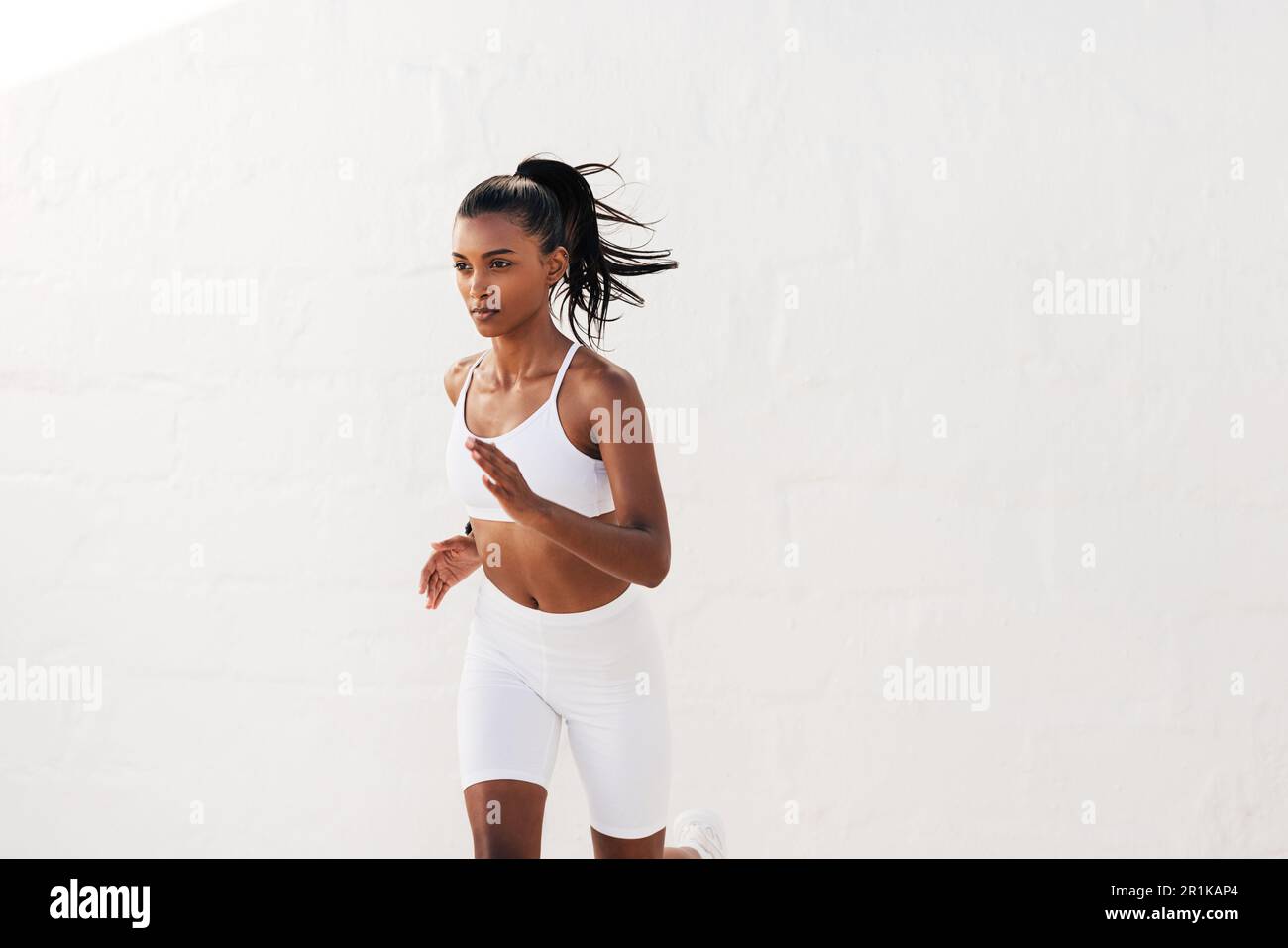 Slim woman in white fitness others running outdoors. Young slim fitness ...