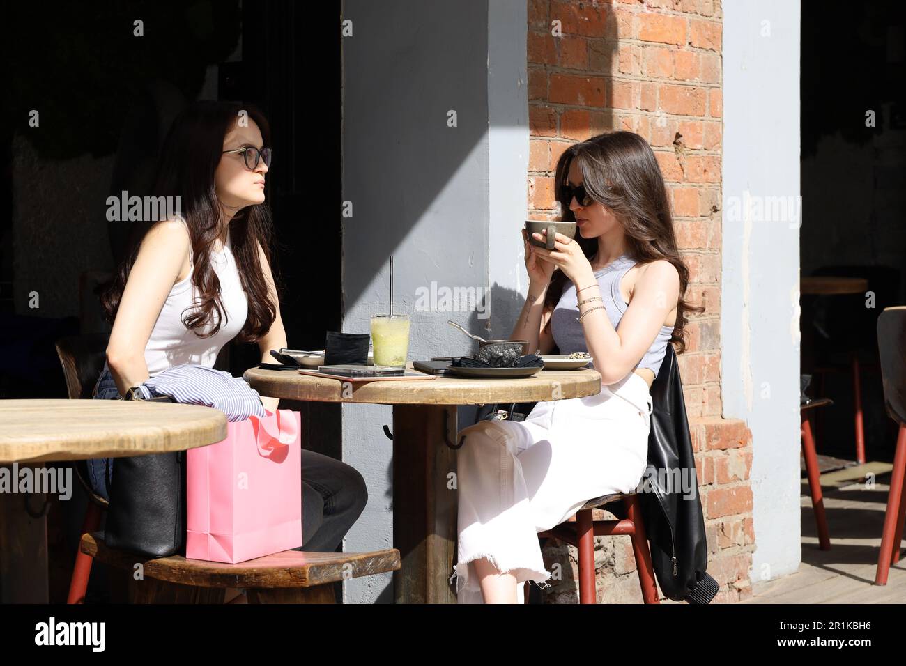Two girls talking while sitting on terrace of street cafe. Life and ...