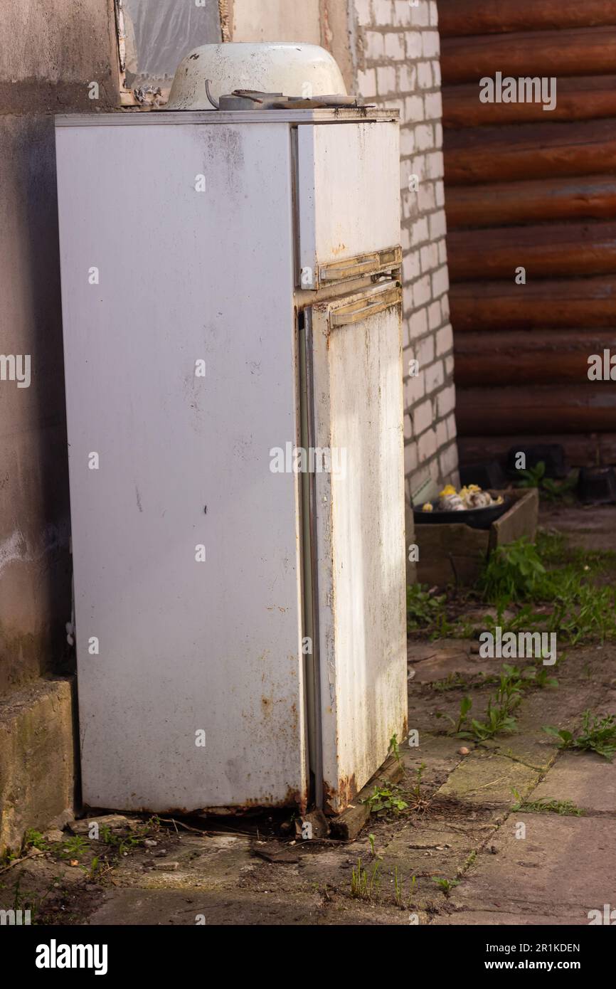 An old rusty refrigerator was thrown away on the street in sun light ...