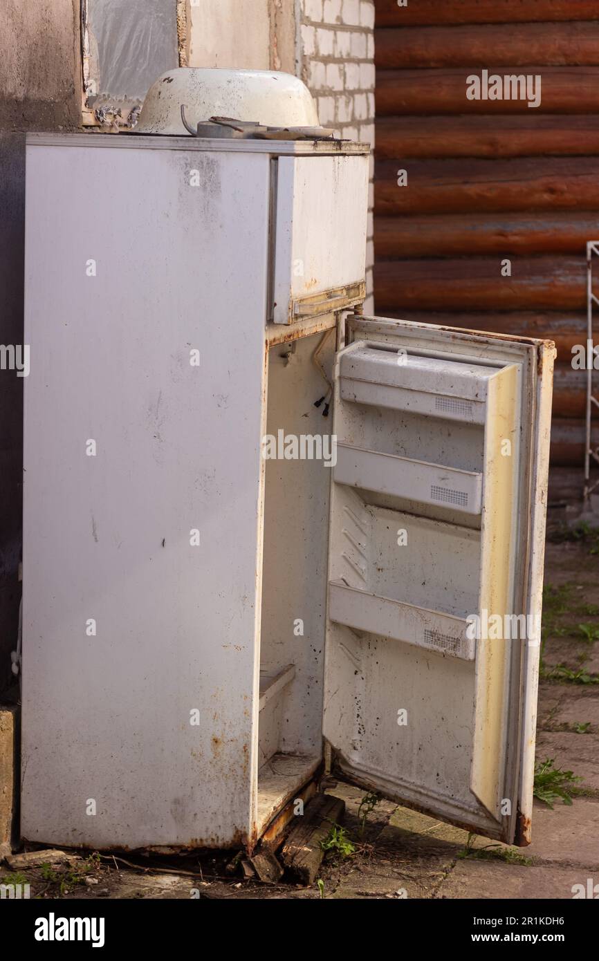 An old rusty refrigerator was thrown away on the street in sun light ...
