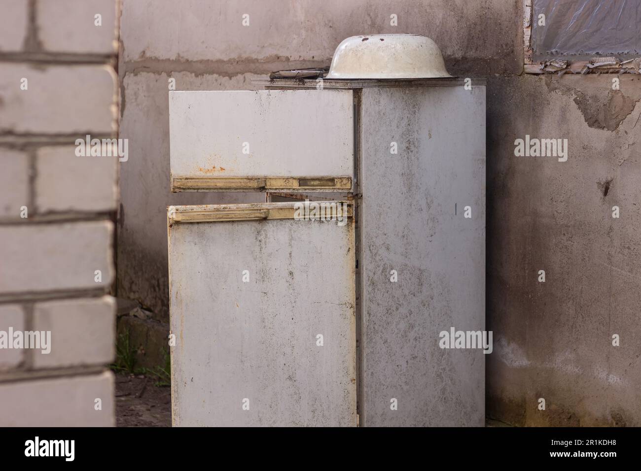 An old rusty refrigerator was thrown away on the street in sun light ...
