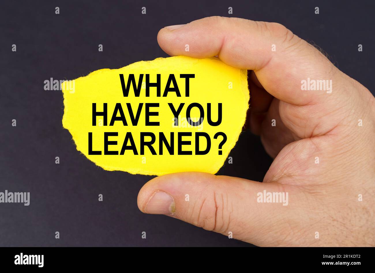 Business concept. On a black background, in the hands of a man, a yellow torn cardboard with the ...