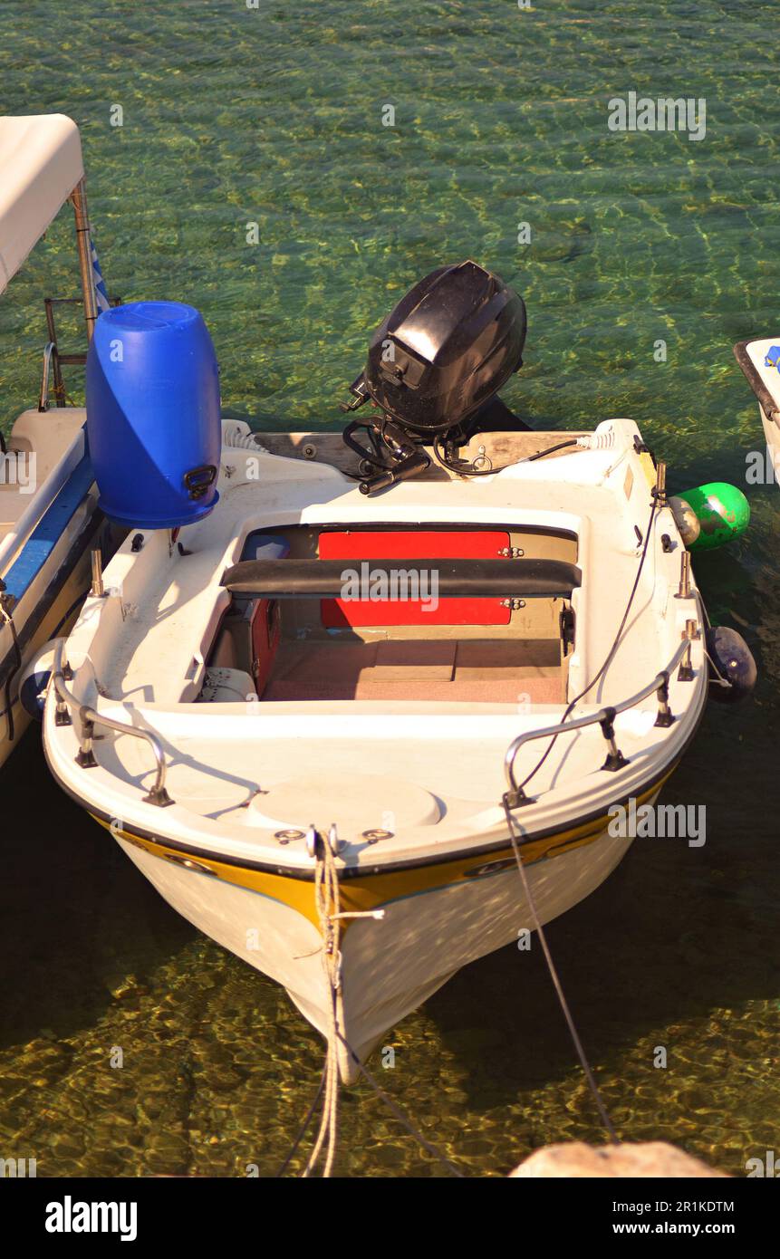 A small motor boat without a canopy is moored in shallow water next to ...