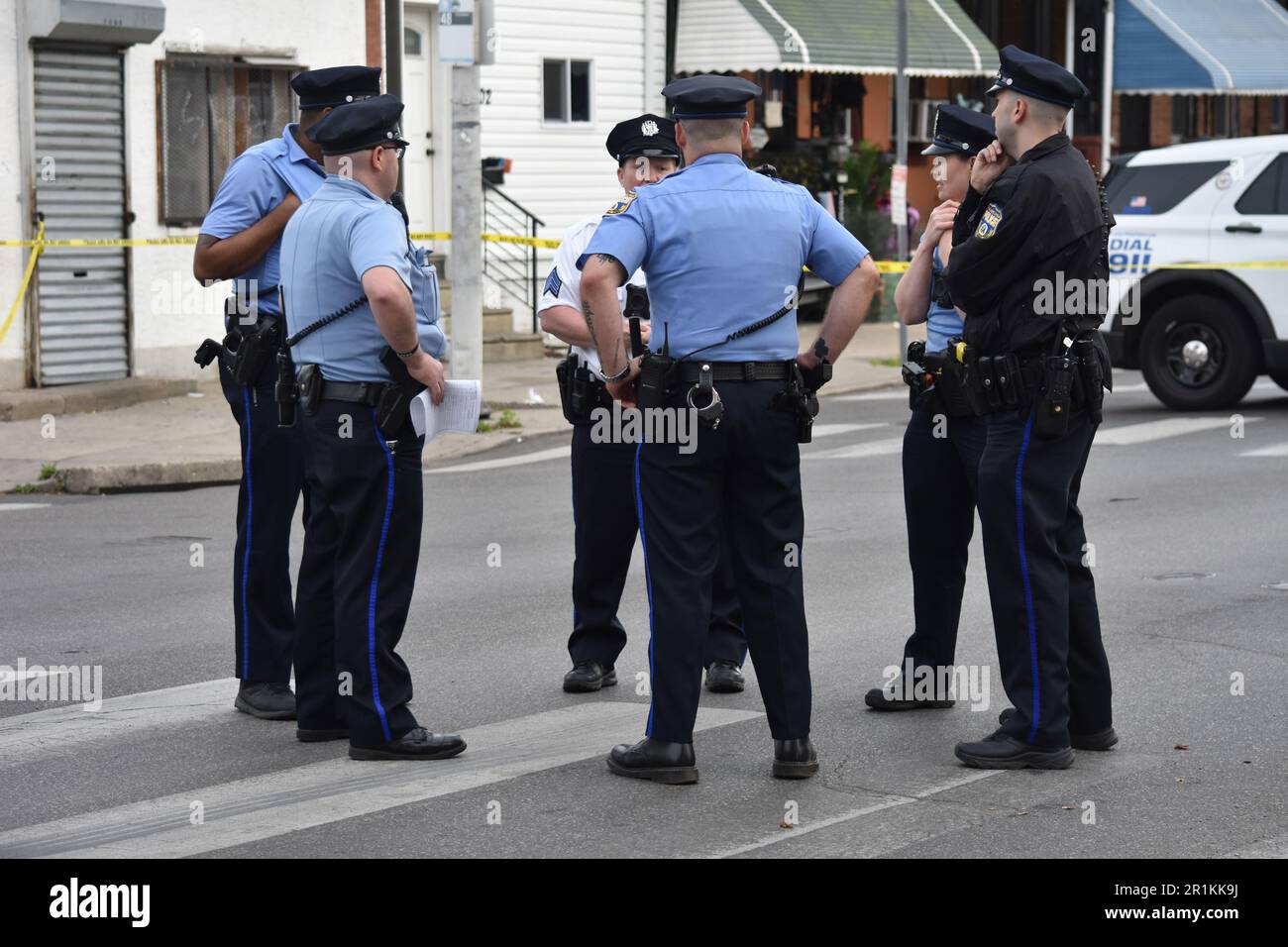 Multiple police officers gather evidence and converse at the crime ...
