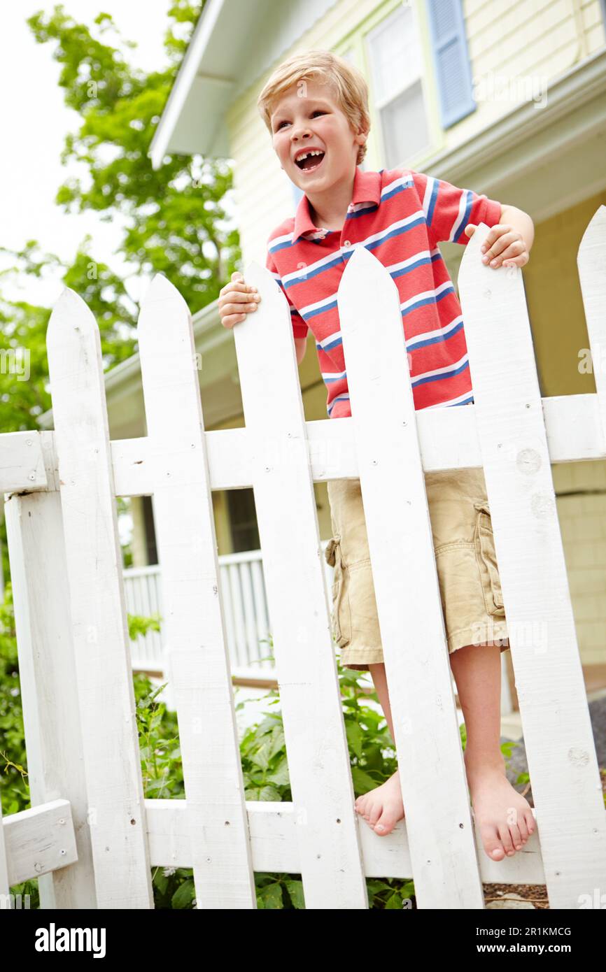 Bye dad. A happy young boy standing on his fence and saying goodbye to ...
