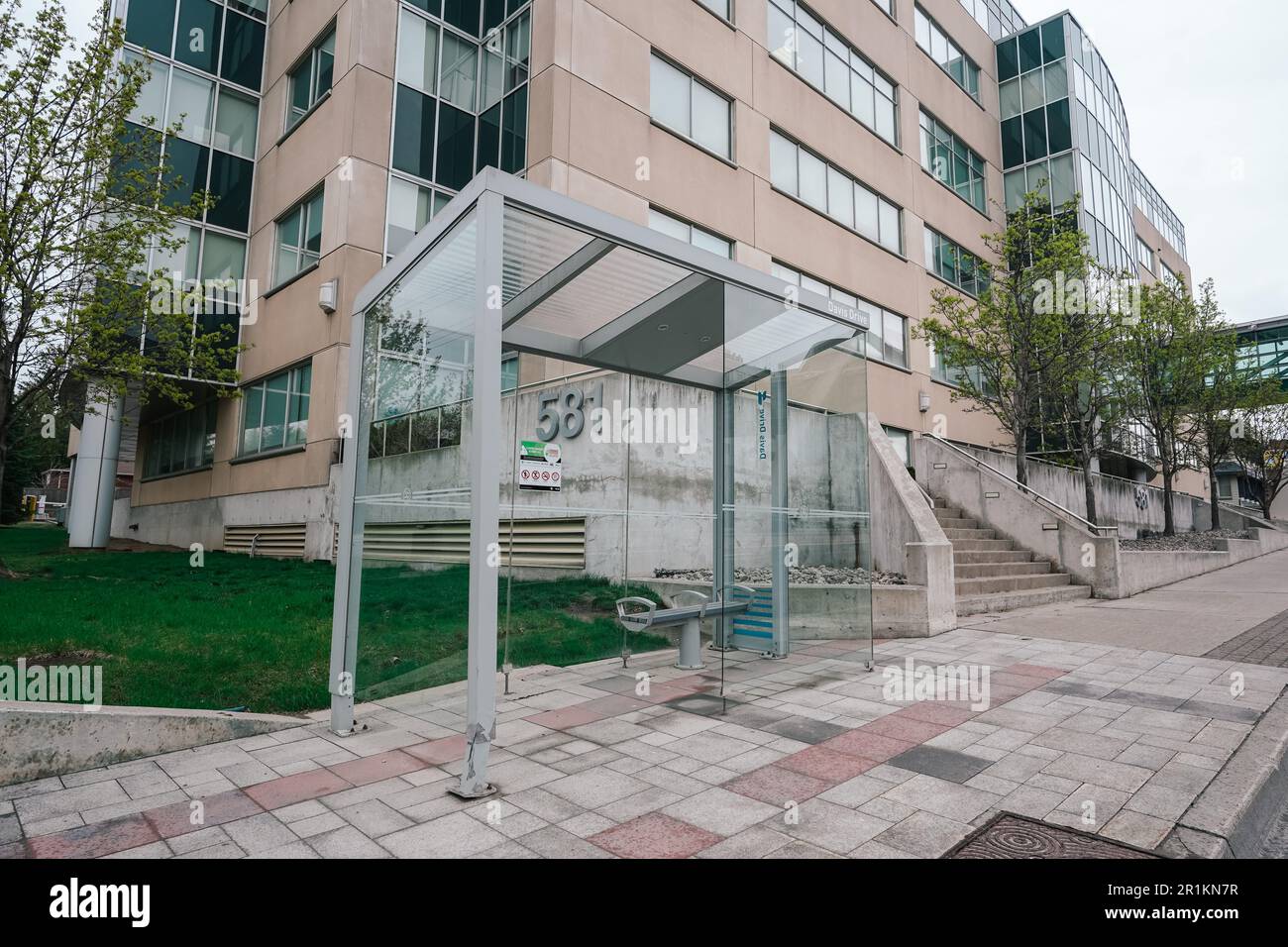 A modern outdoor bus shelter made with glass on interlocking bricks ...
