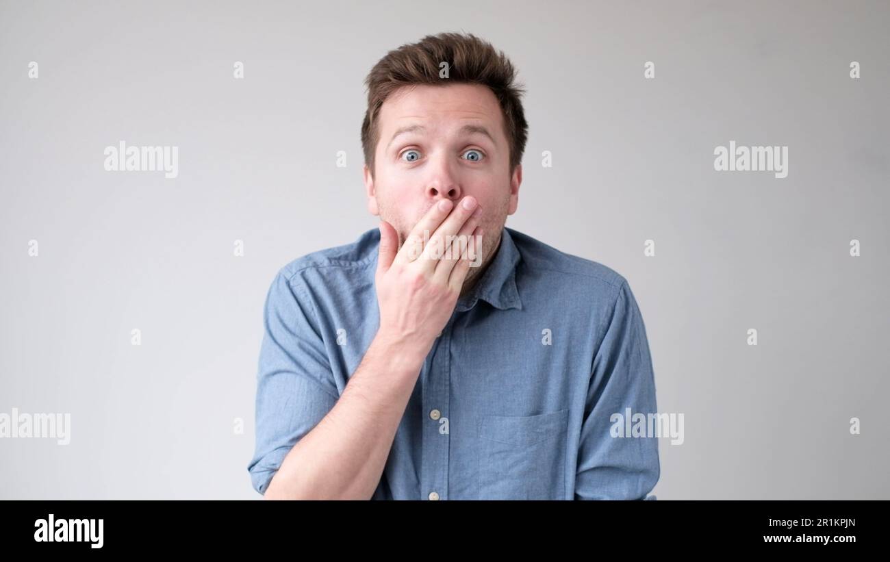 The European young man, in shock, covers his mouth with his hands ...