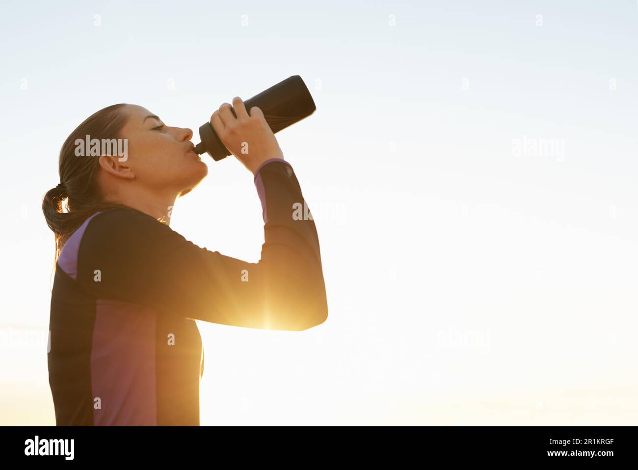 Taking an H2O time out. a female runner drinking from her water bottle ...