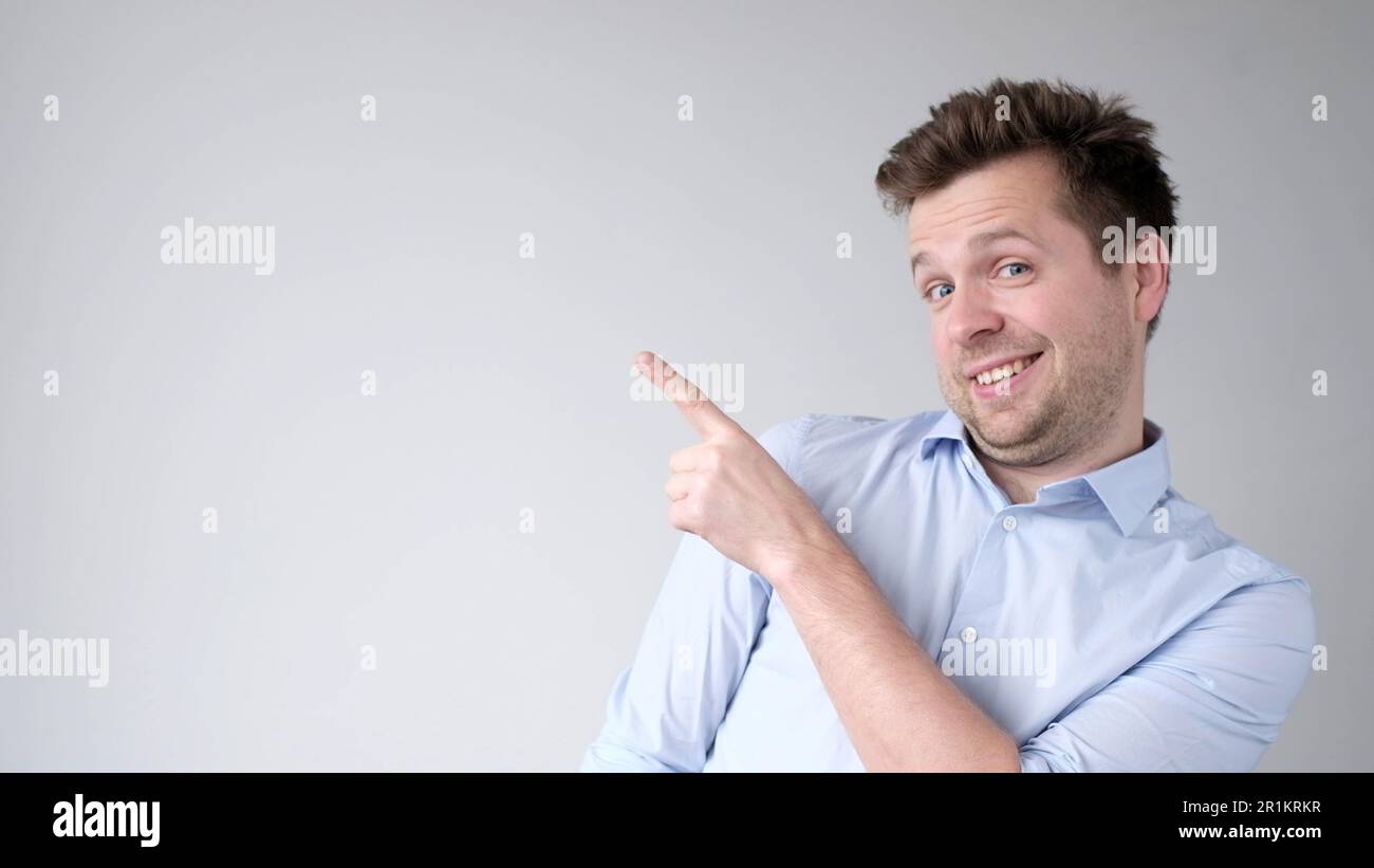 young man points with his index finger towards an empty space for your ...