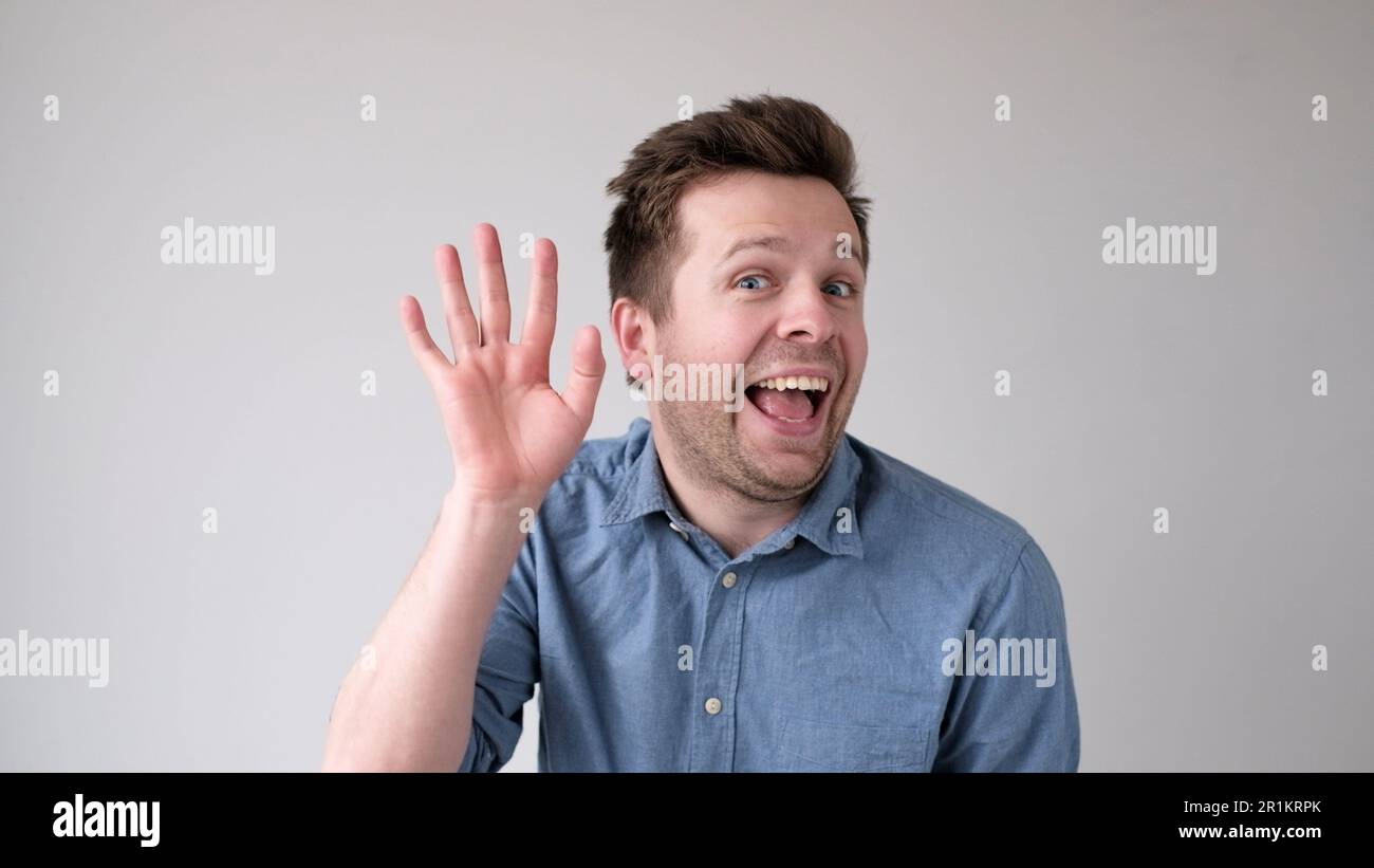 European young man waves his hand, greets his friends Stock Photo - Alamy