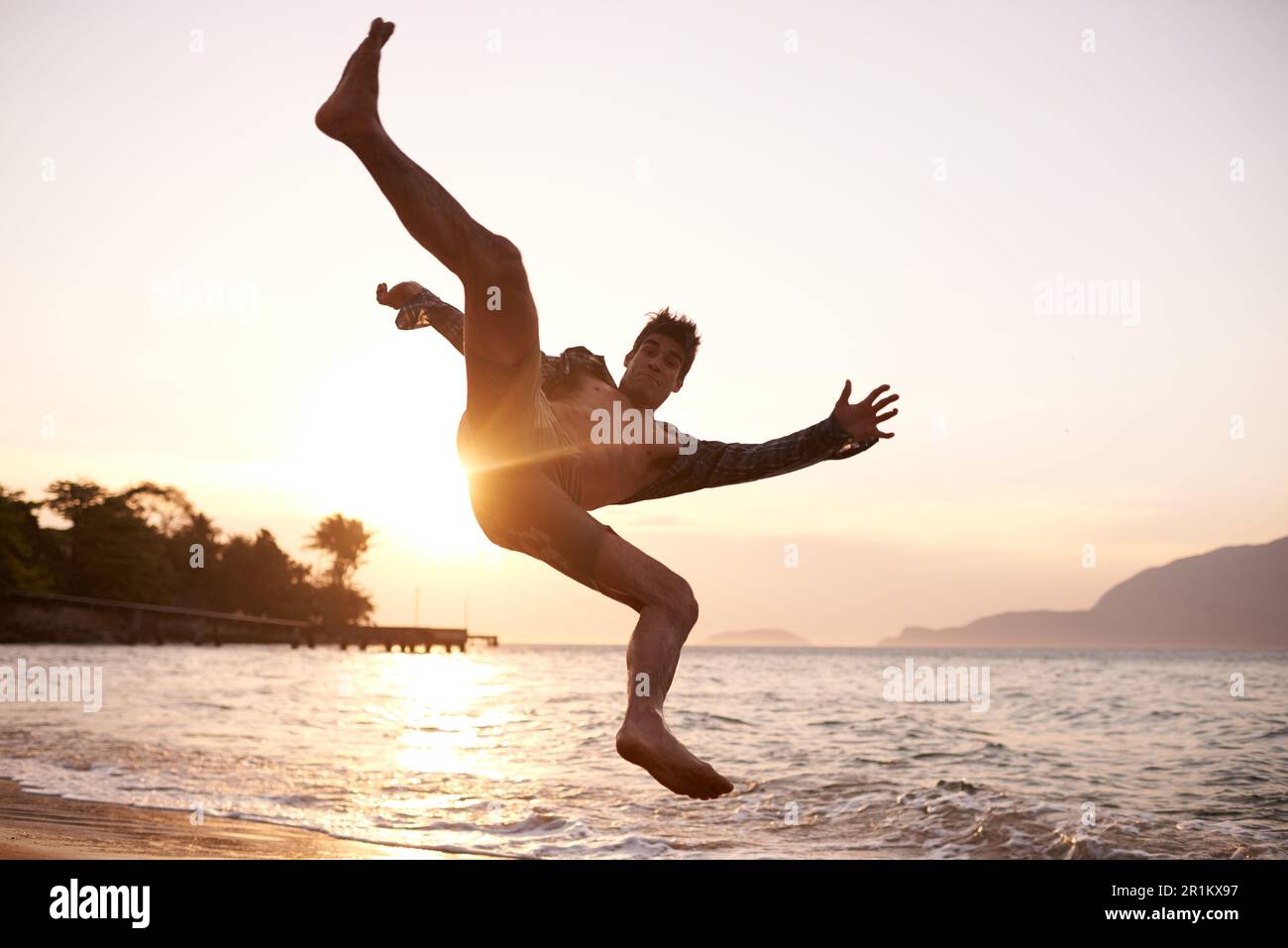 Getting his groove on. a young man dancing on the beach Stock Photo - Alamy