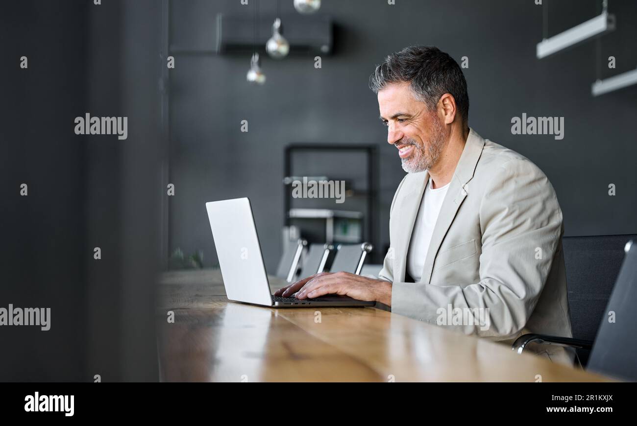 Happy middle aged business man ceo wearing suit sitting in office using laptop Stock Photo - Alamy