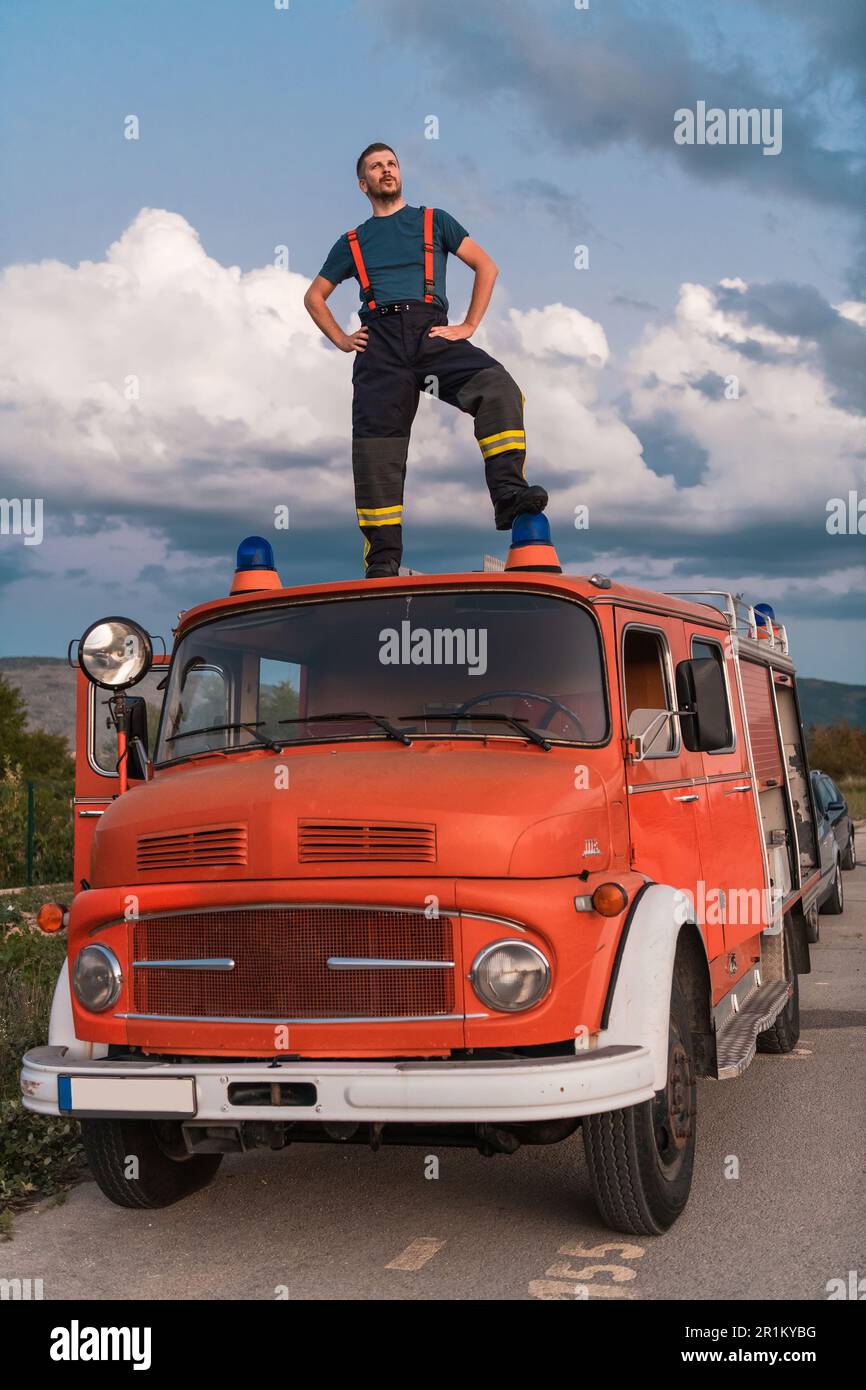 The firefighter standing confidently on the fire truck, ready to ...