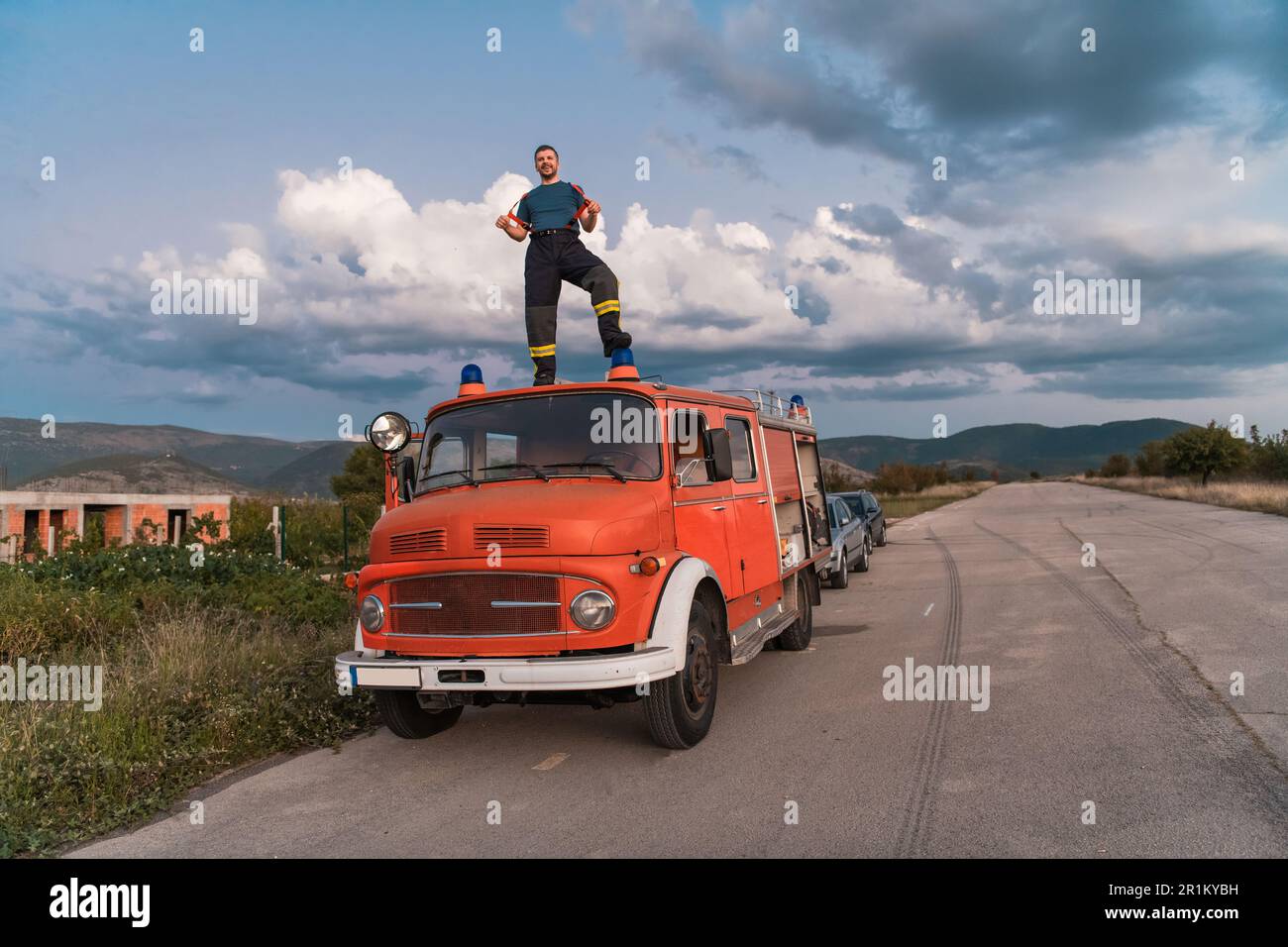 The firefighter standing confidently on the fire truck, ready to ...