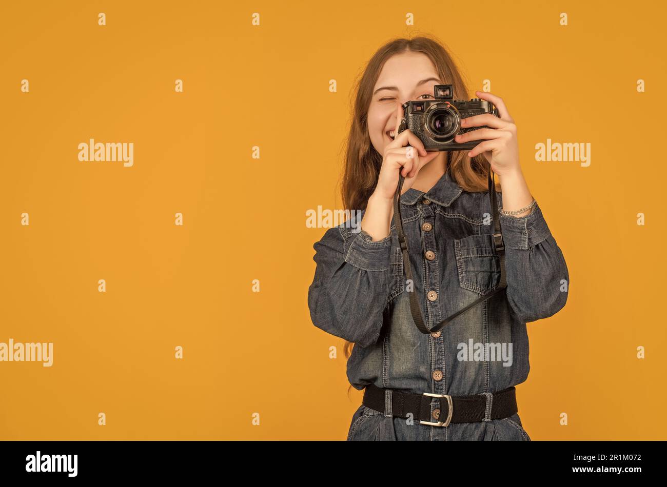 Happy kid photographer looking into camera while photographing yellow ...