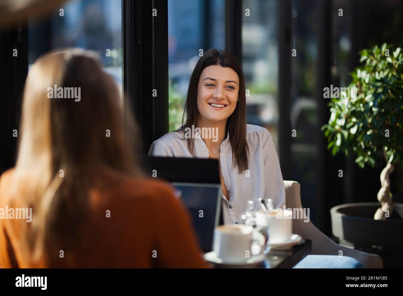Two young business women in a cafe having one on one meeting. Friends ...