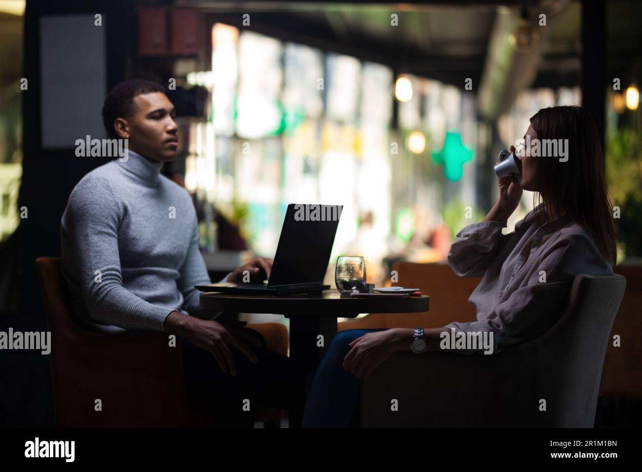 Friends at a cafe after work. Business colleagues working on laptop and ...