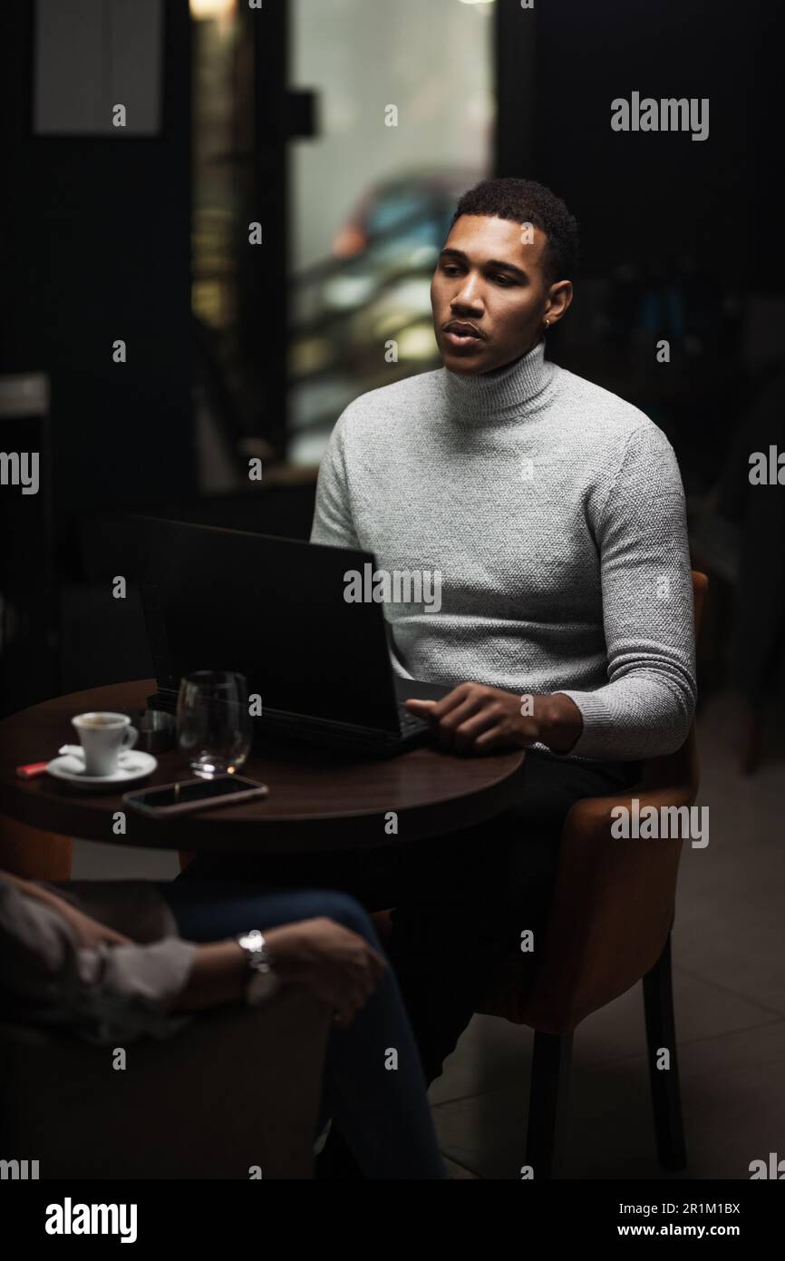 Friends at a cafe after work. Business colleagues working on laptop and ...