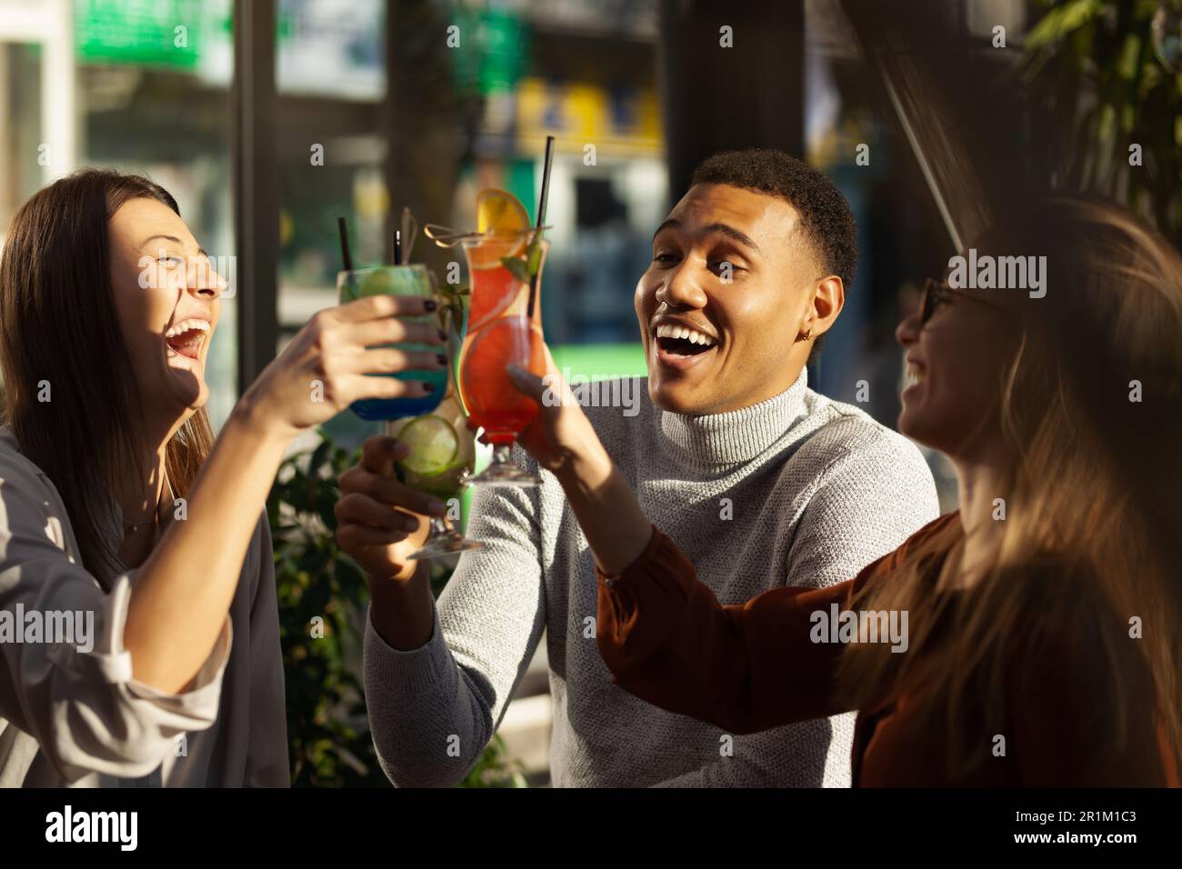 Three multiracial friends in a bar cheering. After work party with ...
