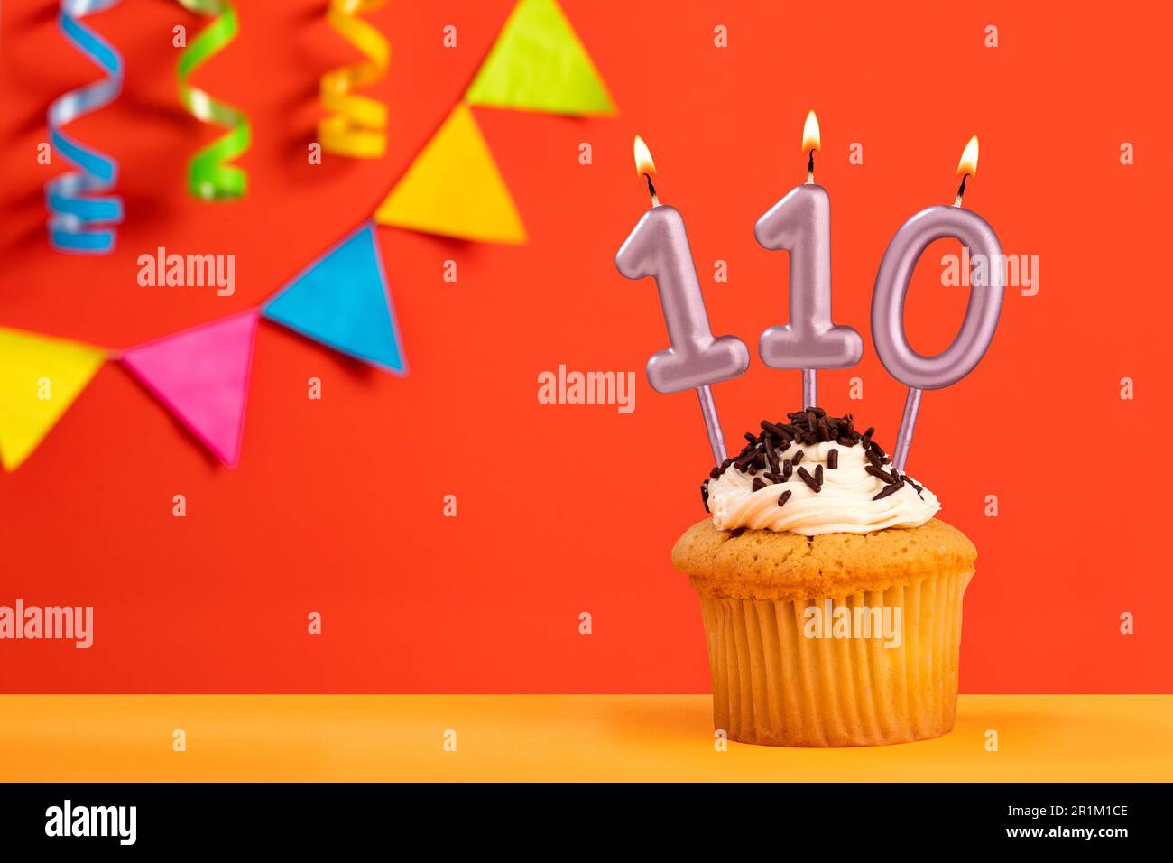 Birthday cake with number 110 candle - Sparkling orange background with ...