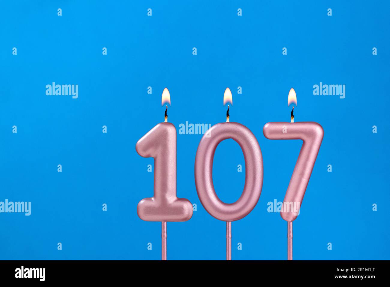 Number 107 - Burning anniversary candle on blue foamy background Stock ...