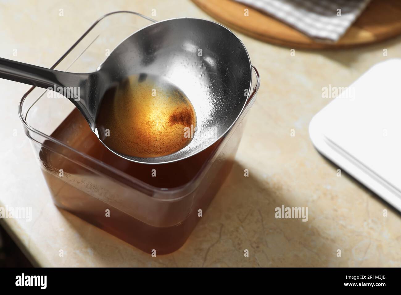 Container and ladle with used cooking oil on beige table Stock Photo ...