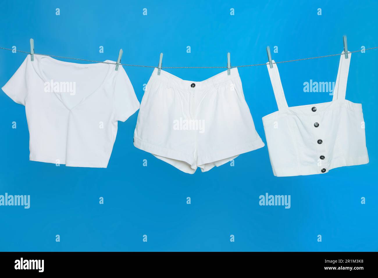 Different clothes drying on laundry line against light blue background ...