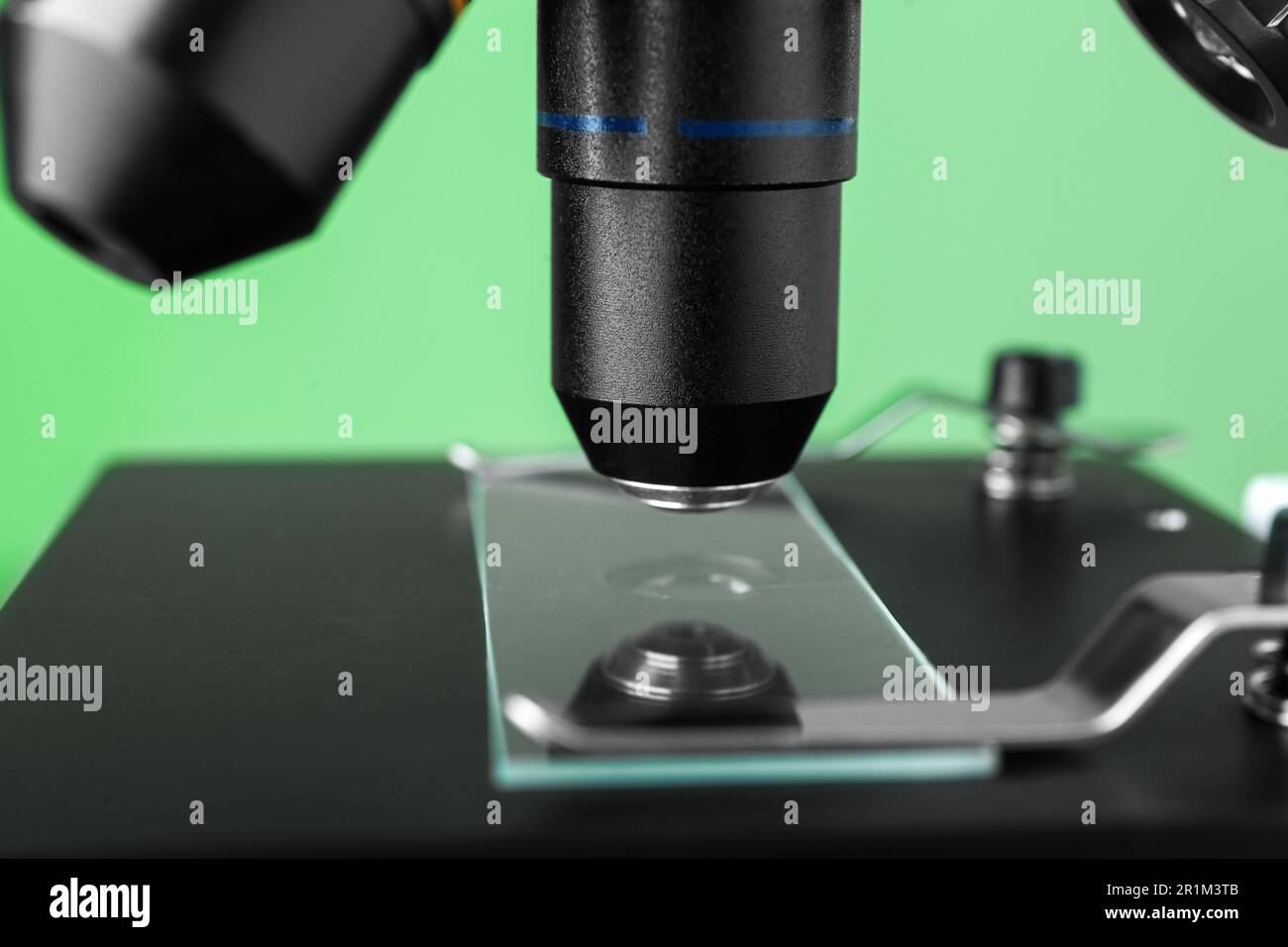 Modern medical microscope with glass slide on green background, closeup ...