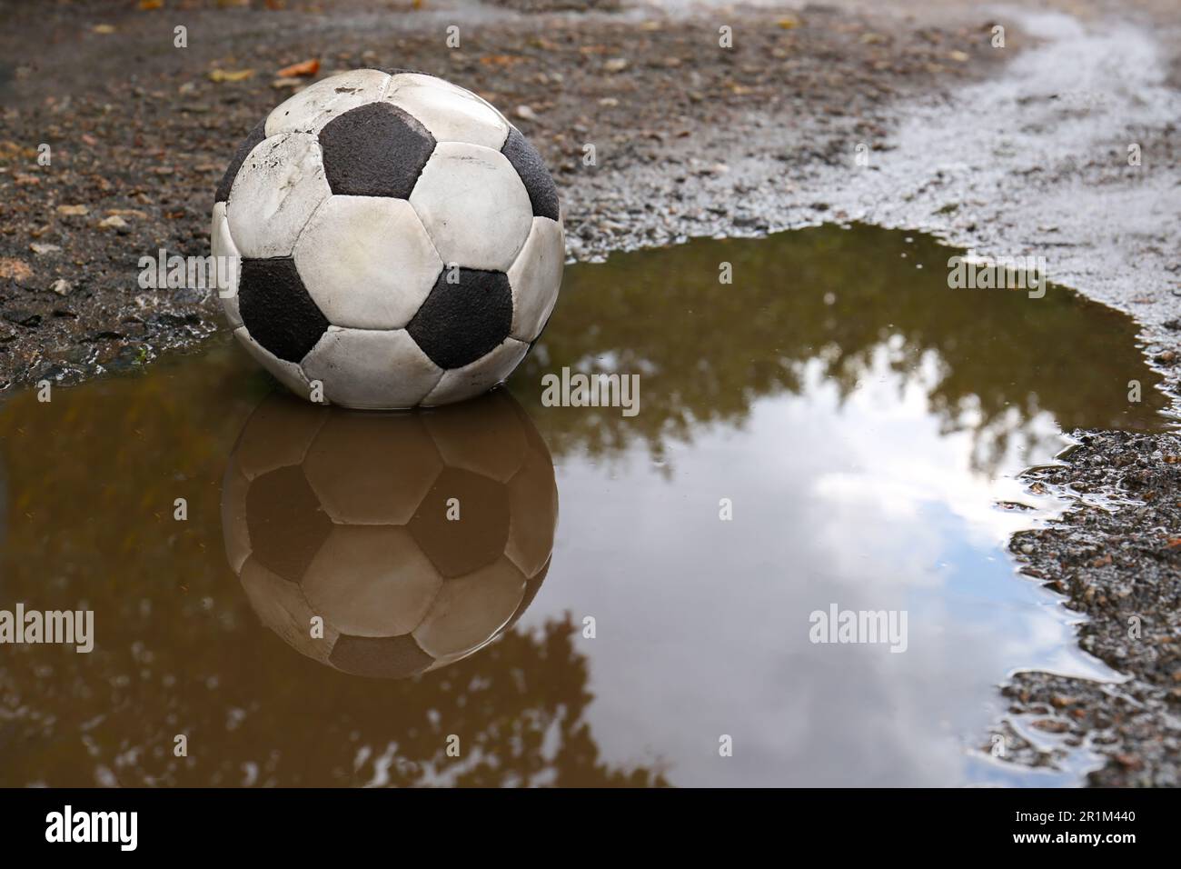 Dirty soccer ball in muddy puddle, space for text Stock Photo - Alamy