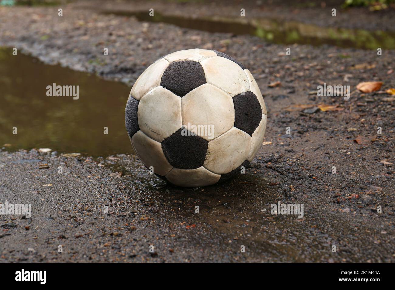 Dirty soccer ball near puddle on ground Stock Photo - Alamy