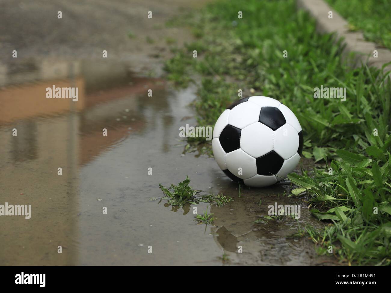 Soccer ball in puddle outdoors, space for text Stock Photo - Alamy