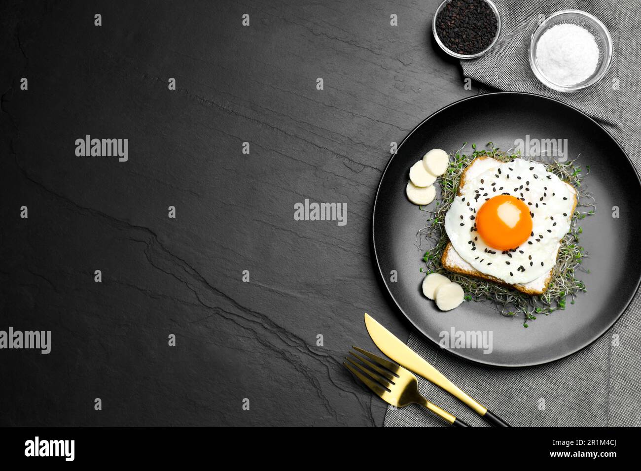 Tasty toast served with egg, cheese and microgreens on black table, top ...