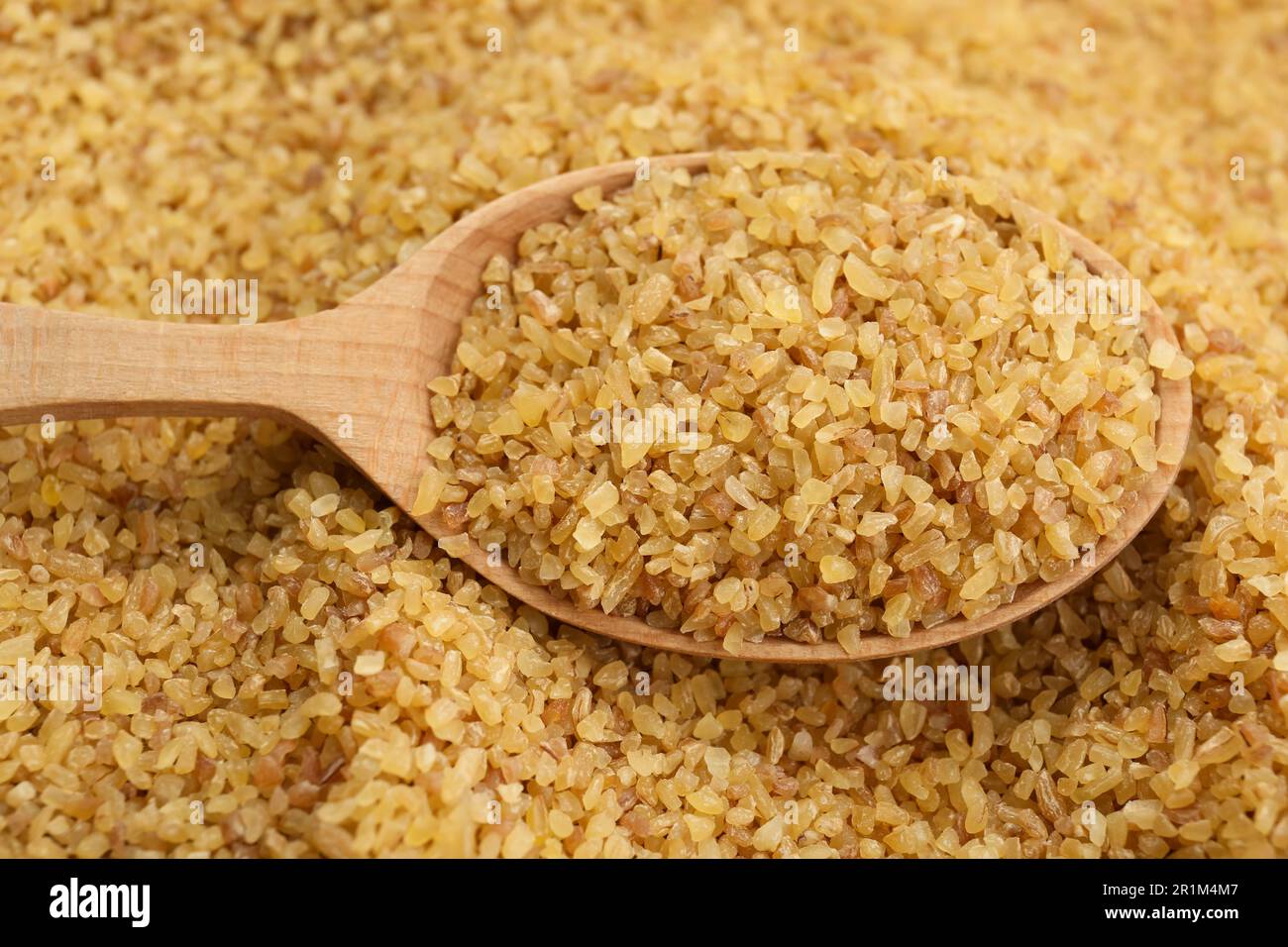 Wooden spoon on pile of uncooked bulgur, closeup Stock Photo - Alamy