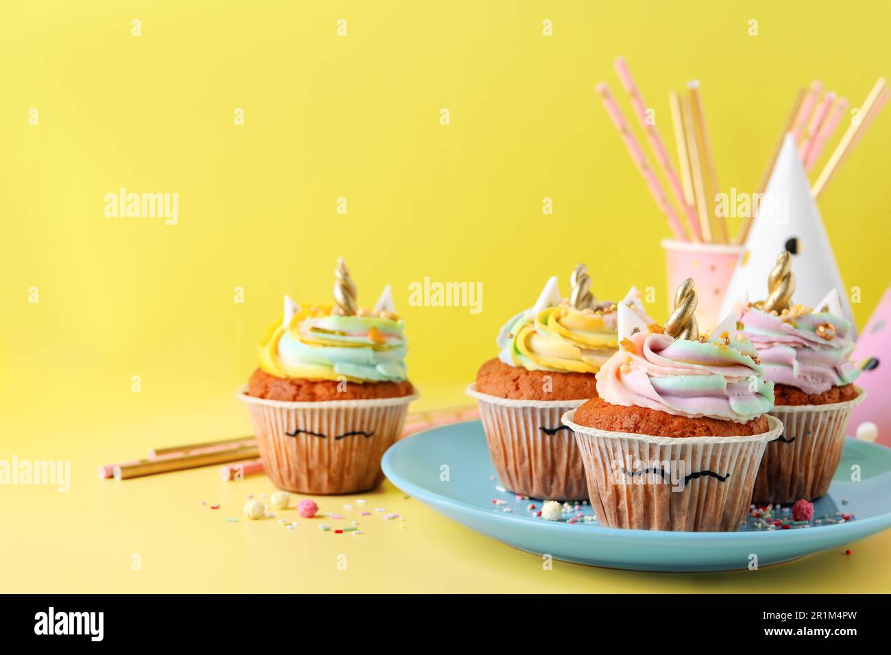 Cute sweet unicorn cupcakes and party items on yellow background, space ...