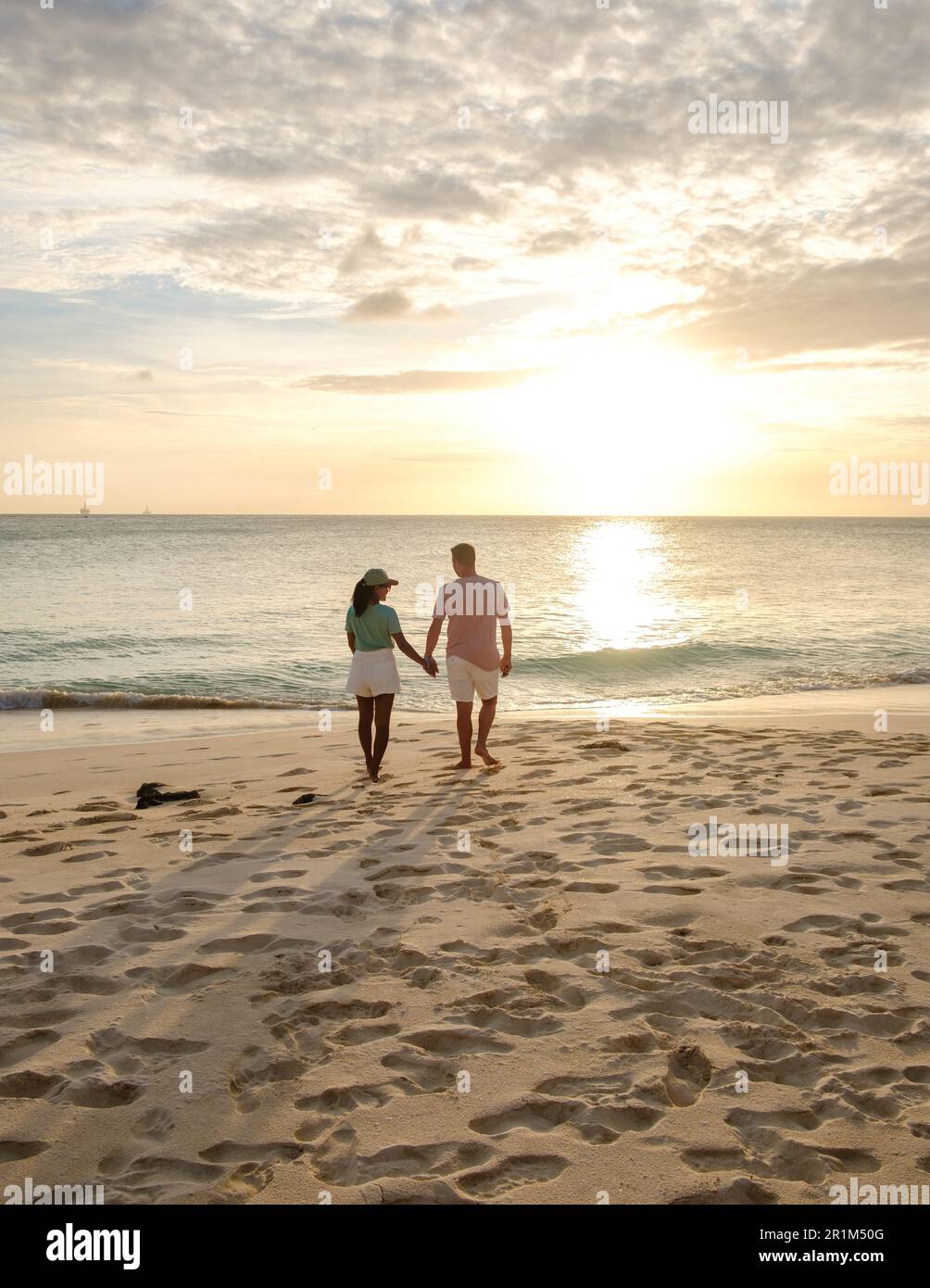 A couple of men and women are on the beach watching the sunset during ...