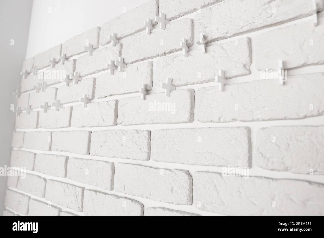 Decorative white bricks with tile leveling system on wall Stock Photo ...