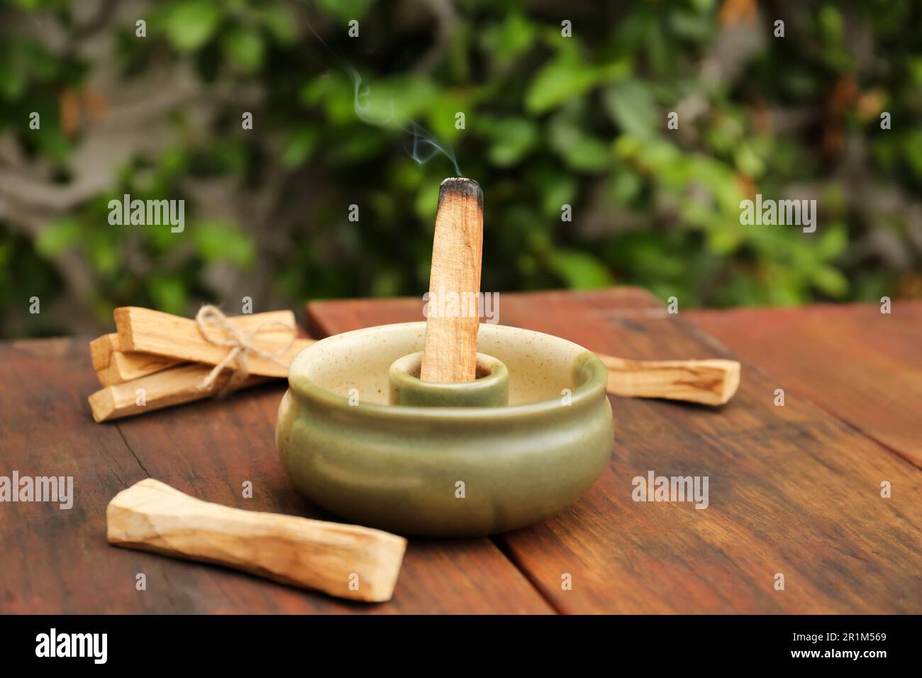 Palo Santo stick smoldering in holder on wooden table outdoors Stock ...