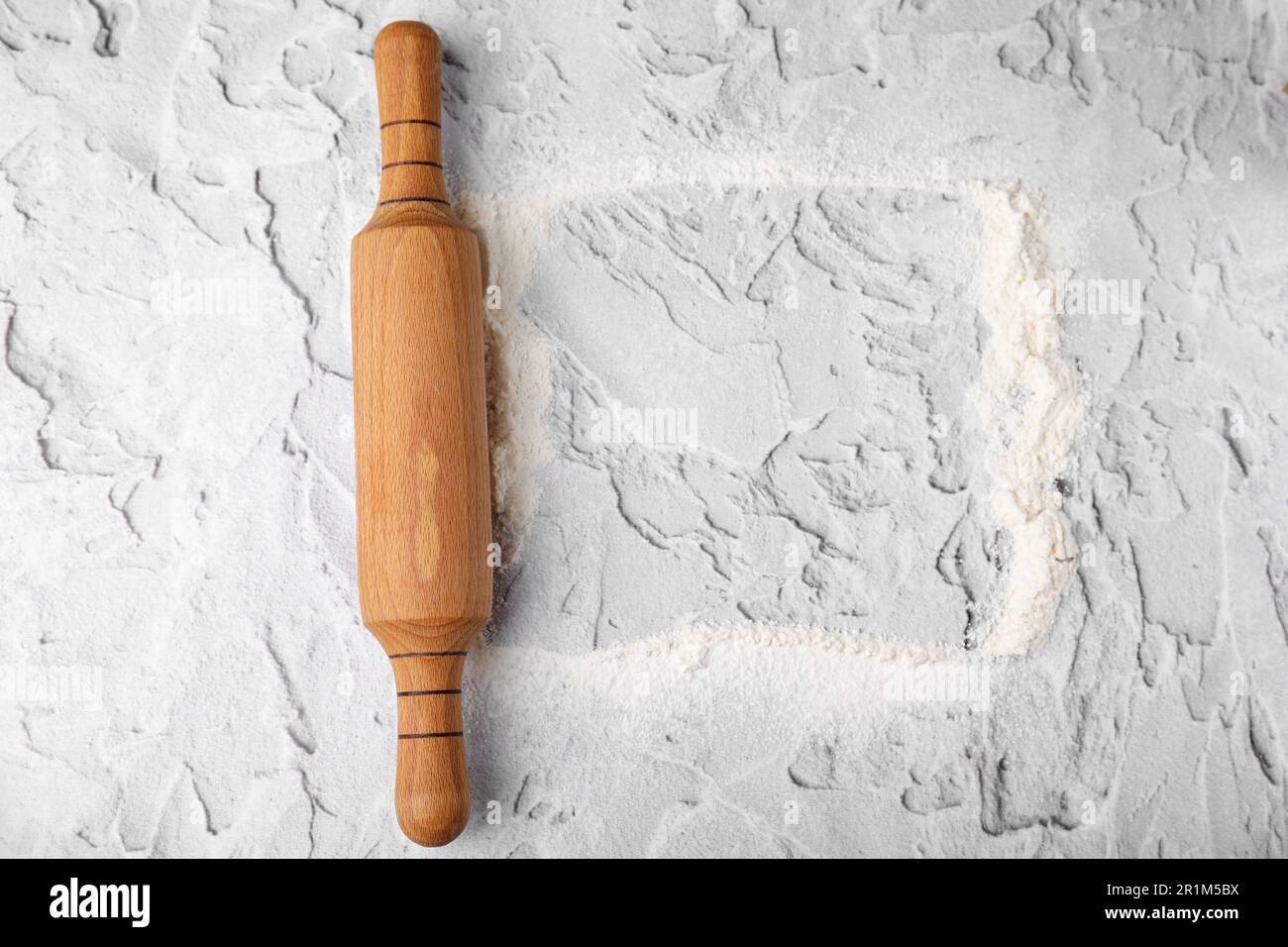 Frame made of flour and rolling pin on white textured table, top view ...