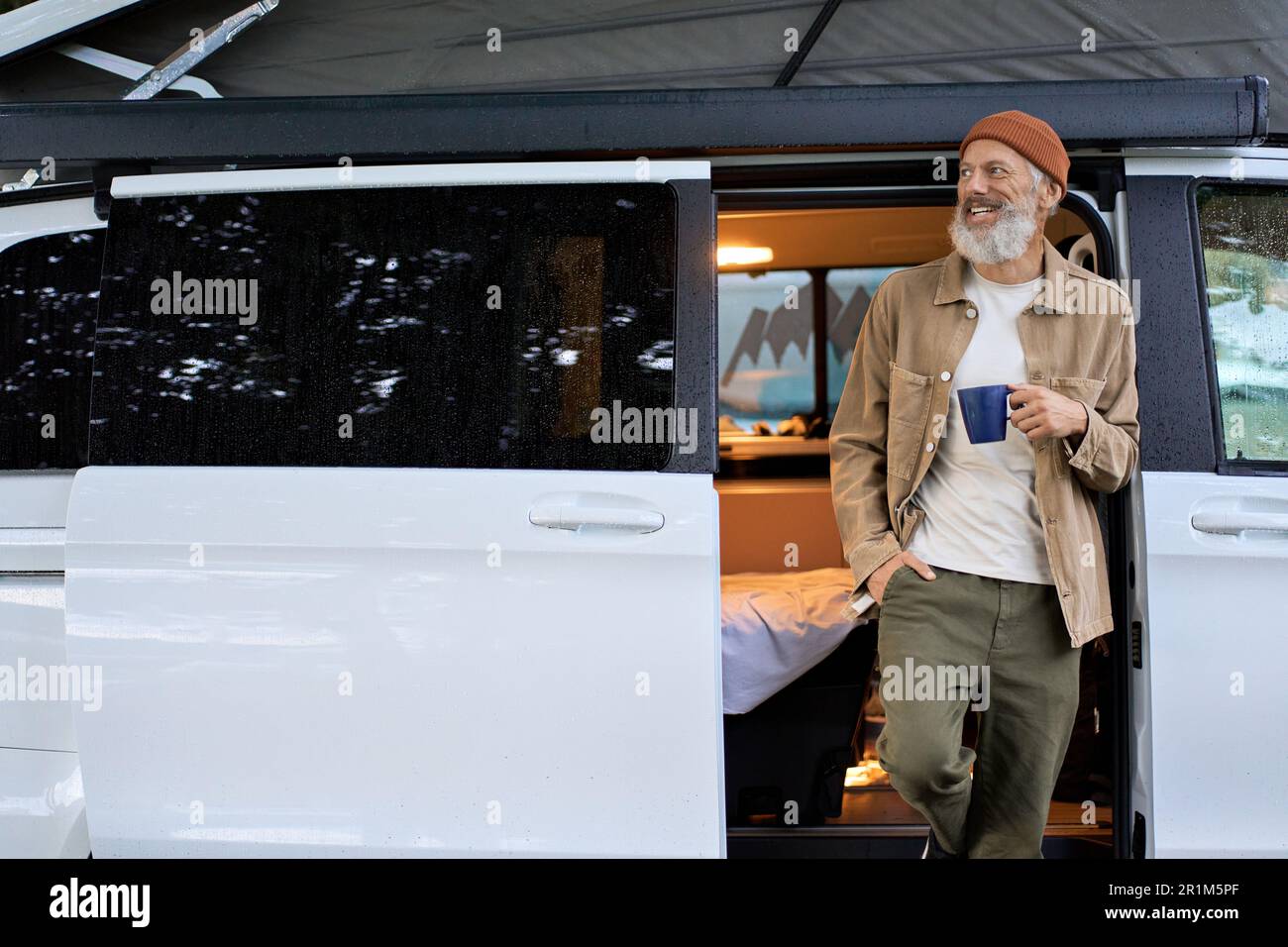 Older man traveler standing near rv camper van drinking coffee enjoying ...