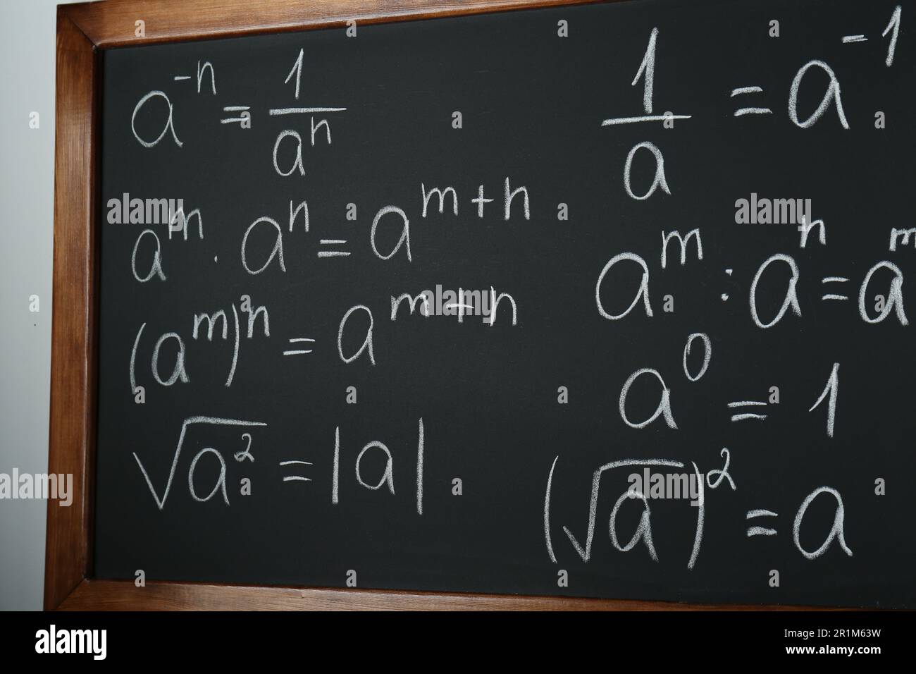 Chalkboard with many different math formulas on white wall, closeup ...