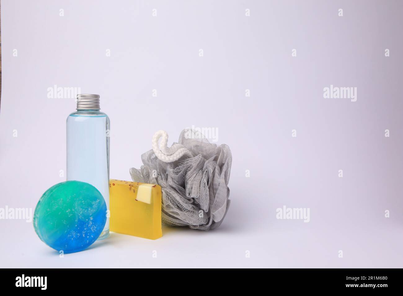 Grey shower puff and cosmetic products on white background, space for ...