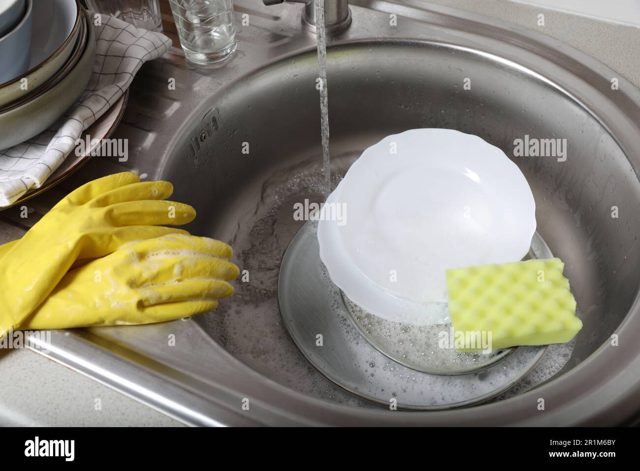 Washing plates, sponge and rubber gloves in kitchen sink Stock Photo ...