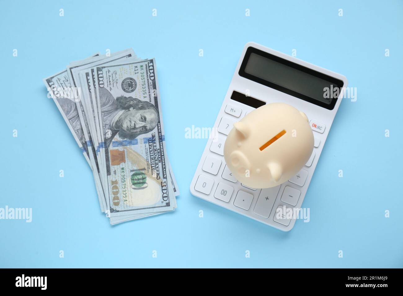Piggy bank, banknotes and calculator on light blue background, flat lay ...