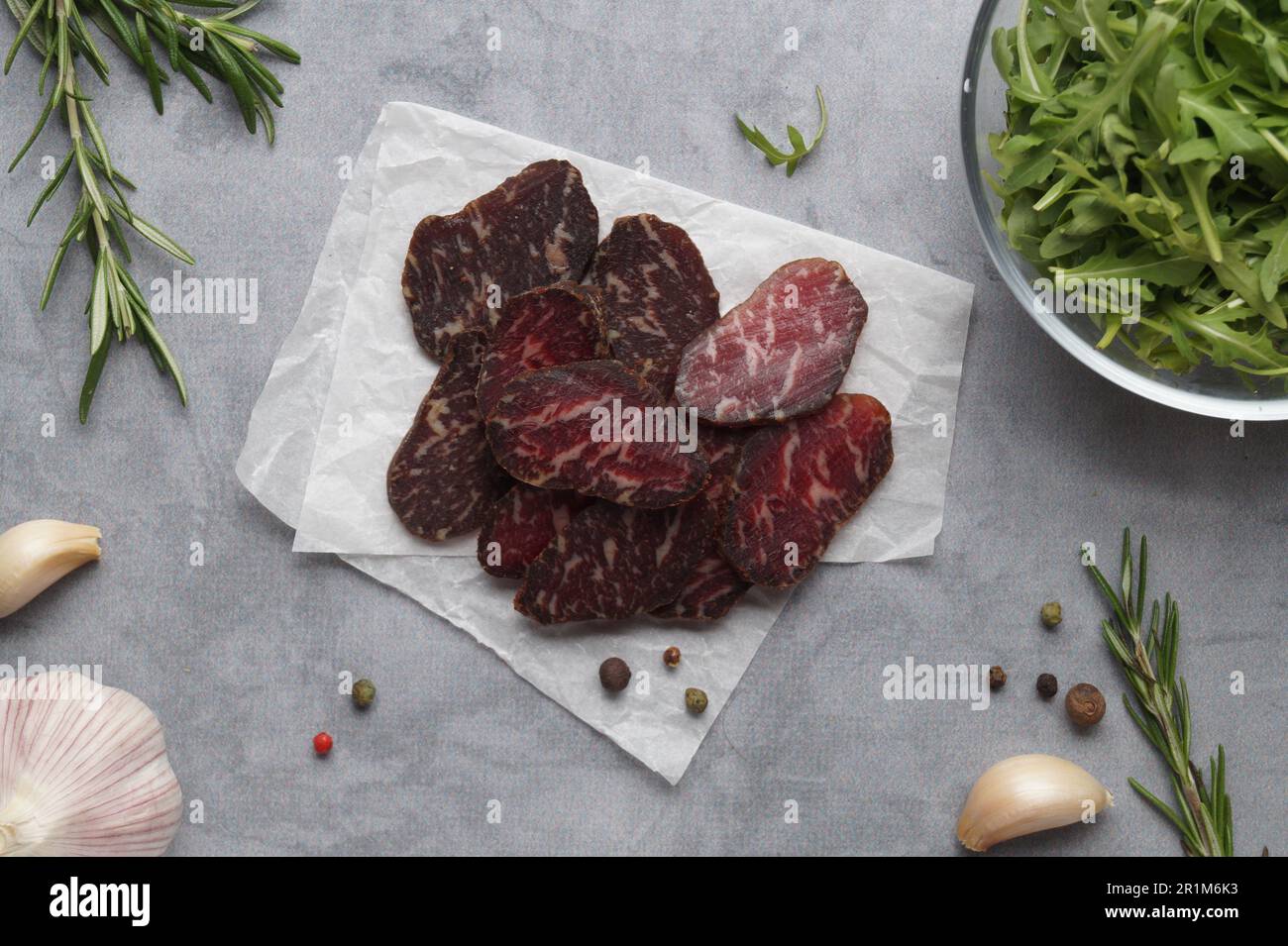 Slices of delicious beef jerky and spices on grey marble table, flat ...