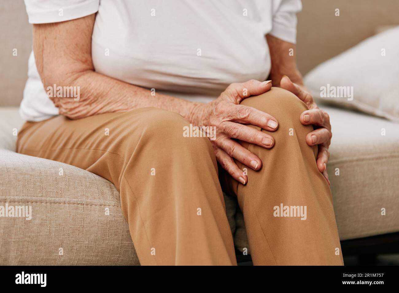 Elderly woman severe pain in her leg sitting on the couch, health ...