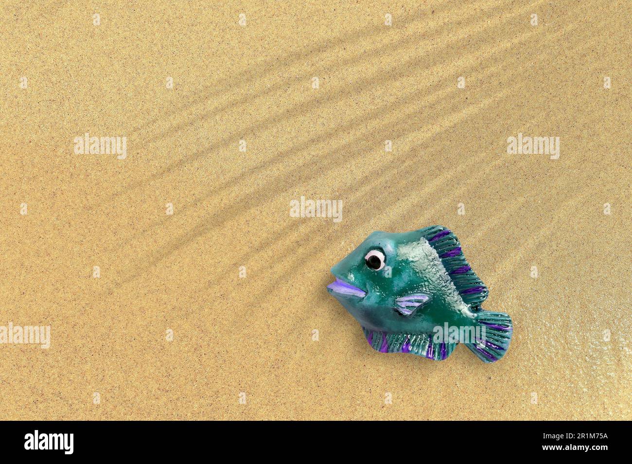 Top up view of green rubber fish on sand beach. vacation concept ...
