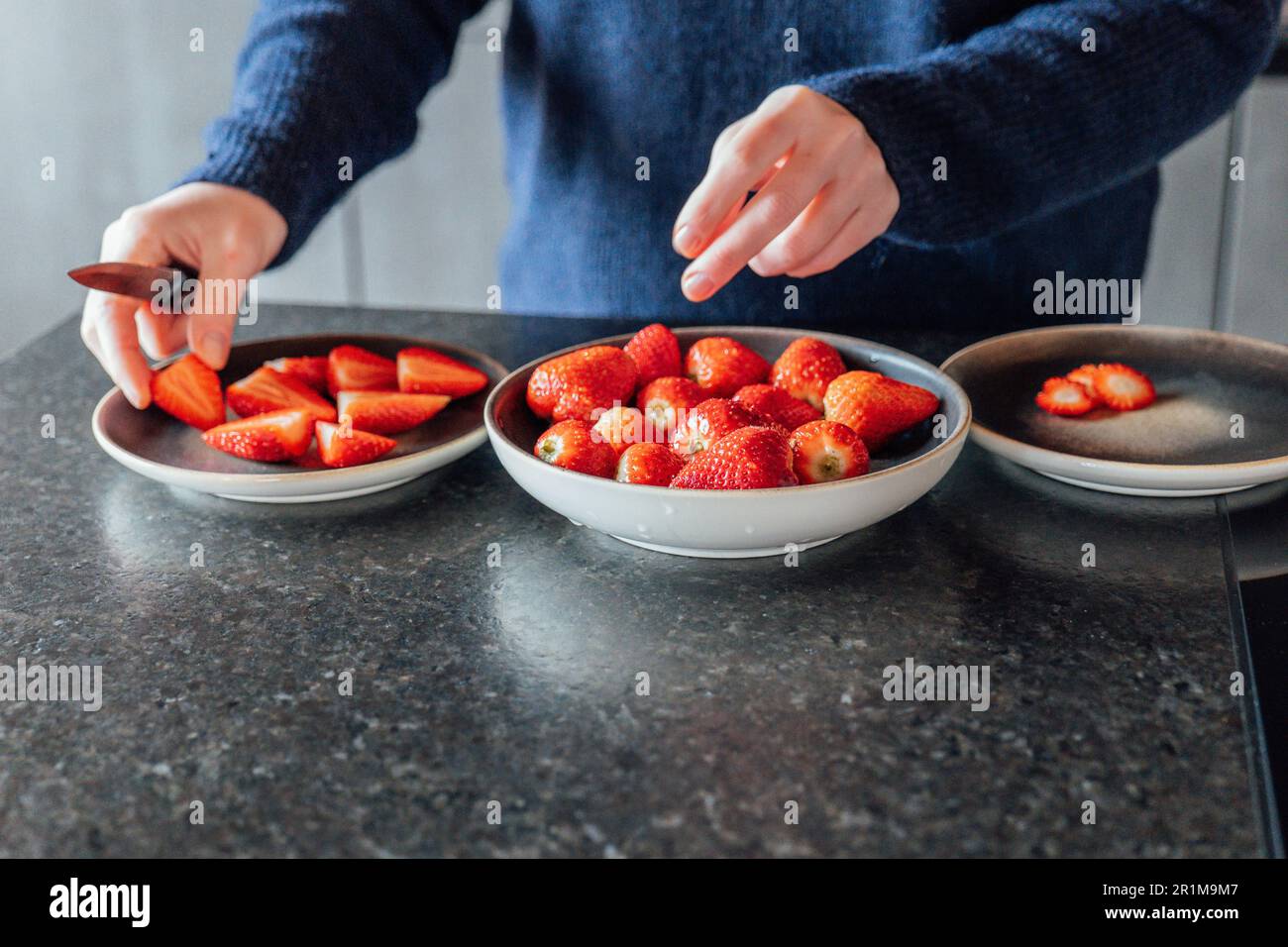 strawberries cutting.Hands cut strawberries and put in a plate ...