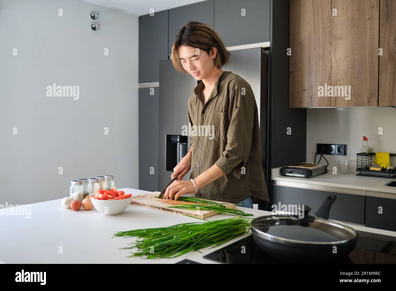 Asian young man cutting chinese chive at kitchen Stock Photo - Alamy