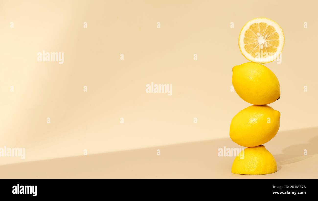 A pyramid of juicy yellow lemons on a beige background. Creative ...