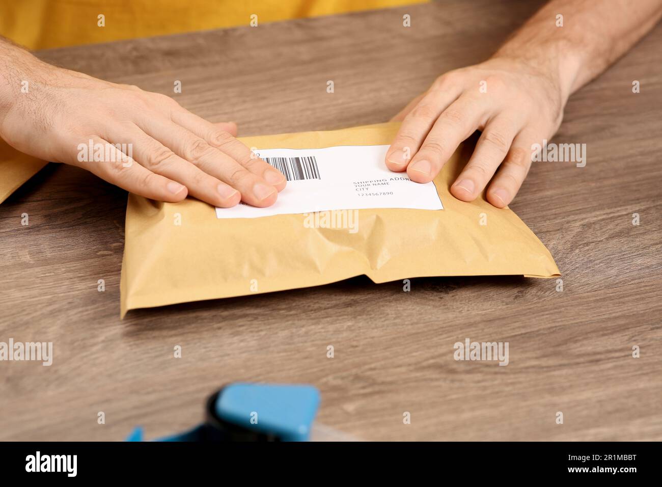 Post office worker sticking barcode on parcel at counter indoors ...